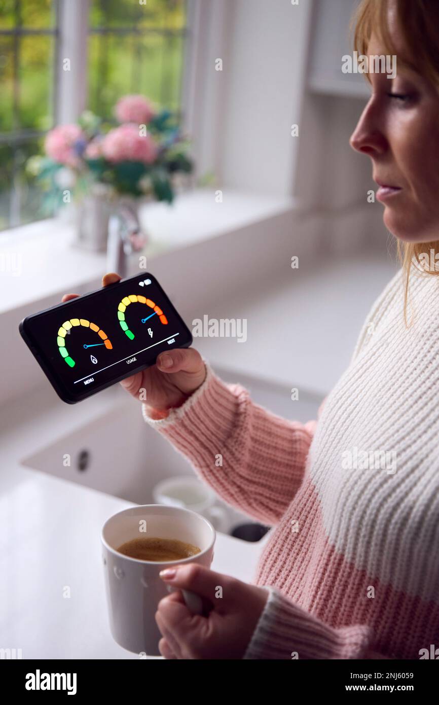 Worried Woman Looking At Smart Meter In Kitchen At Home During Cost Of ...
