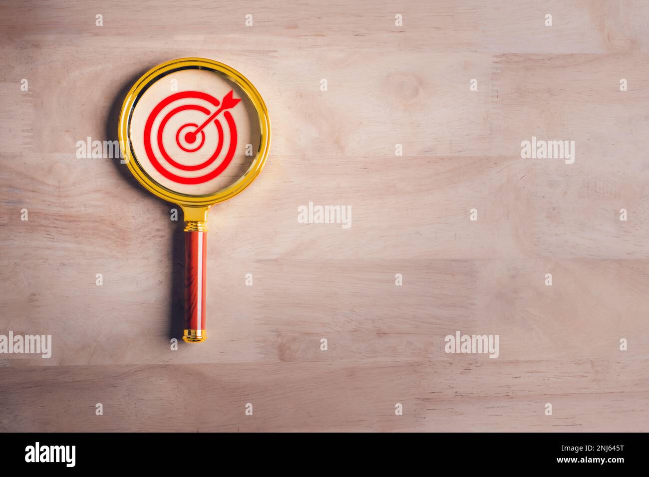 Magnifying glass with goal target on wooden table. CRM, Customer ...
