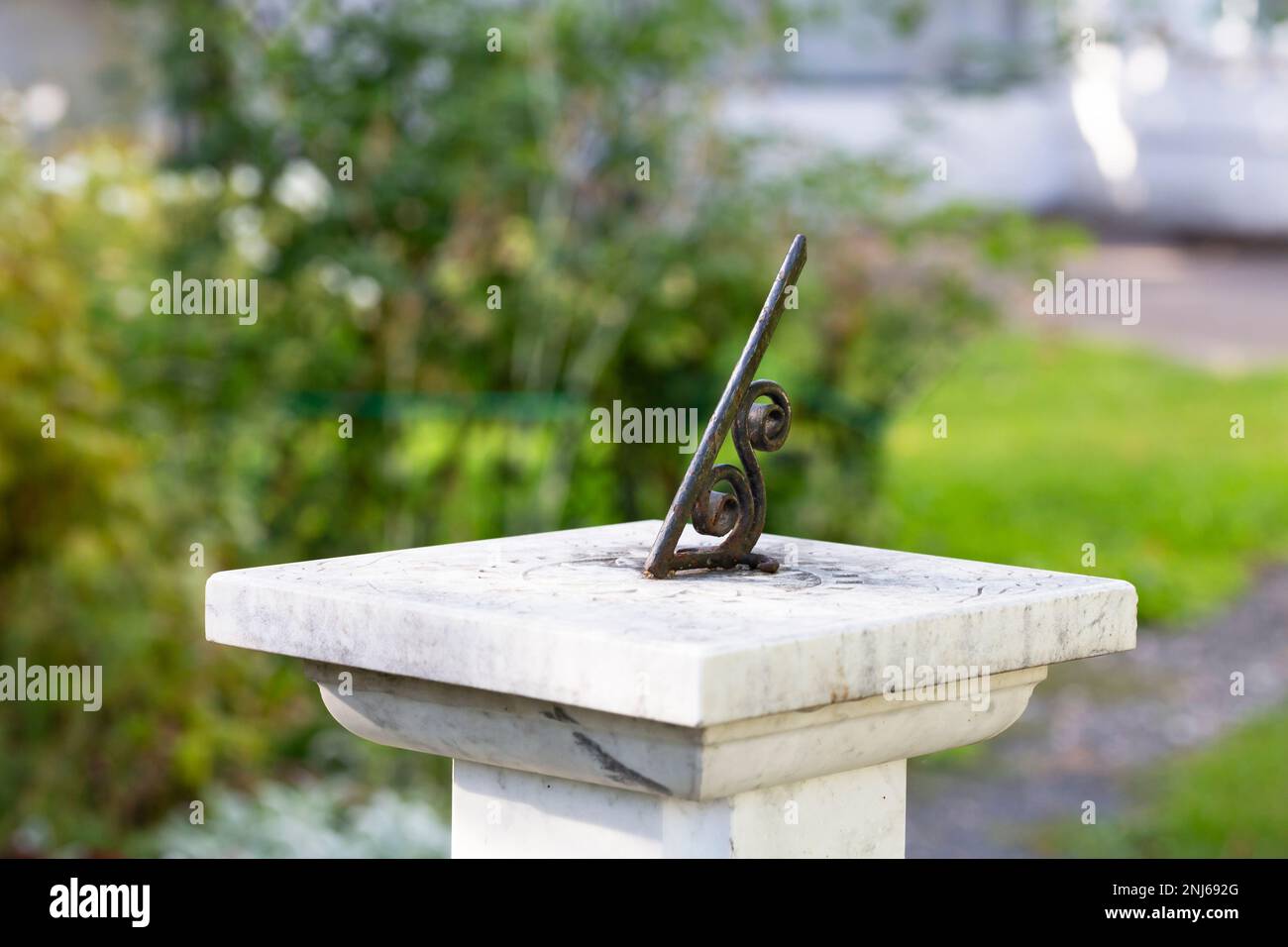 A vintage sundial with green patina throws a long shadow, tracking the ...