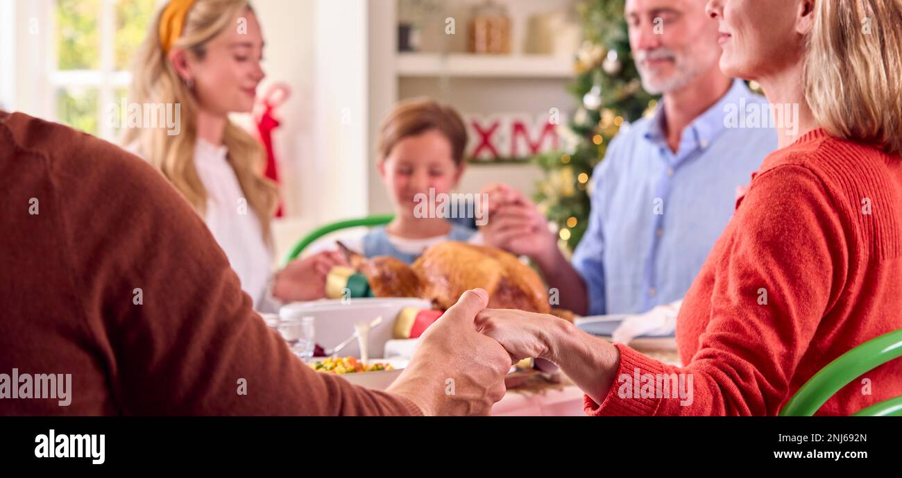 Multi-Generation Family Celebrating Christmas At Home Saying Prayer ...