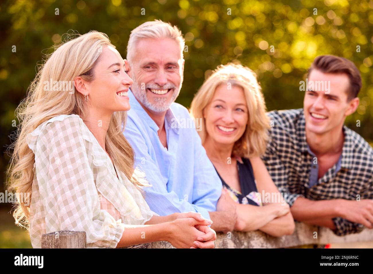 Multi-Generation Family With Adult Offspring Leaning On Fence Walking ...