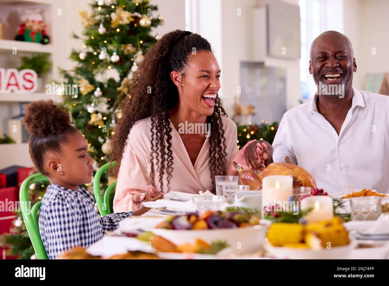 Multi-Generation Family Celebrating Christmas At Home Saying Prayer ...