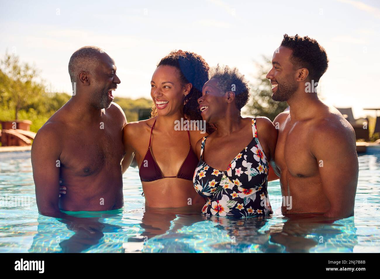 Multi-Generation Family With Adult Offspring On Summer Holiday Relaxing In Swimming Pool ...