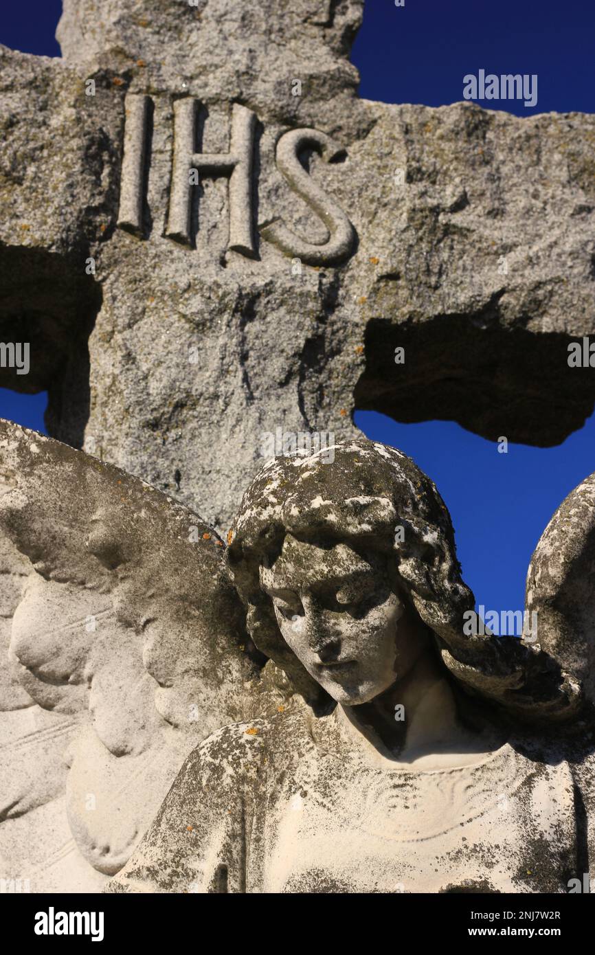 A beautiful young woman angel looking down from a cross with the IHS ...