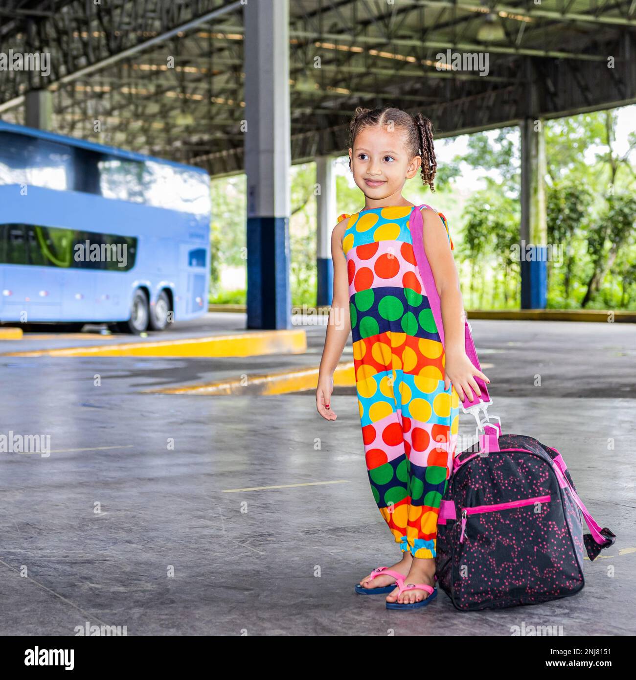 Little latina and brazilian girl with a big bag waiting for a bus at ...