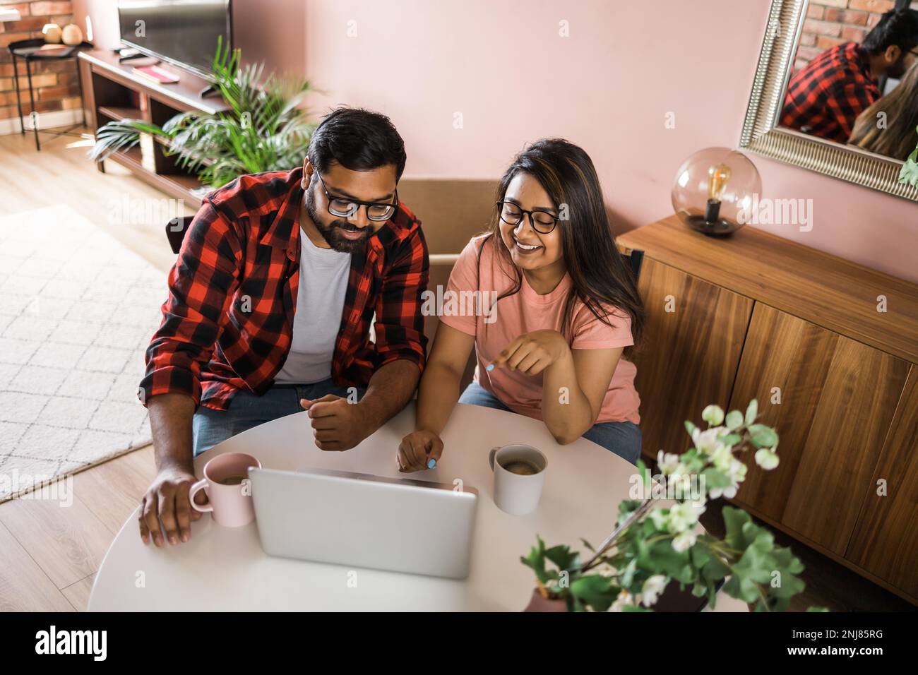 Happy indian family couple cuddle at desk make video call to friends ...