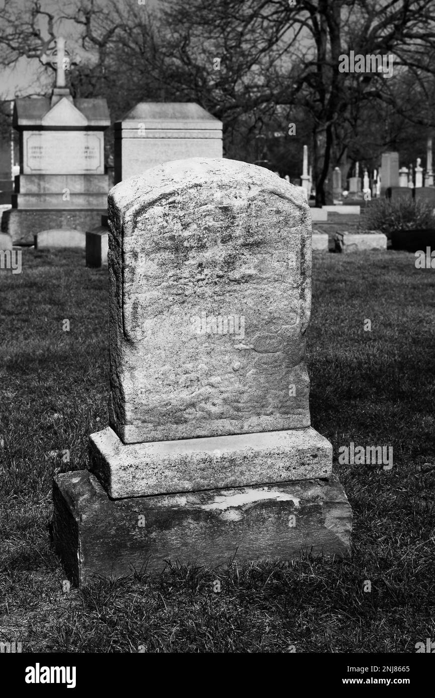 A worn and weathered old tombstone with a blank epitaph and room for ...