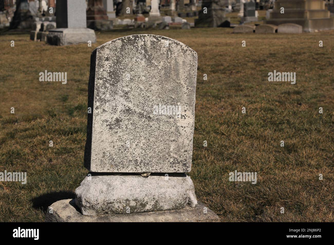 A worn and weathered old tombstone with a blank epitaph and room for ...