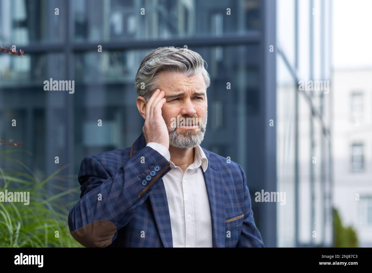 Mature fair-haired man outside office building has dizziness and ...
