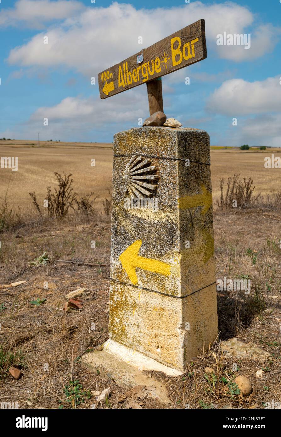 A weathered stone signpost, emblazoned with the scallop shell symbol of ...