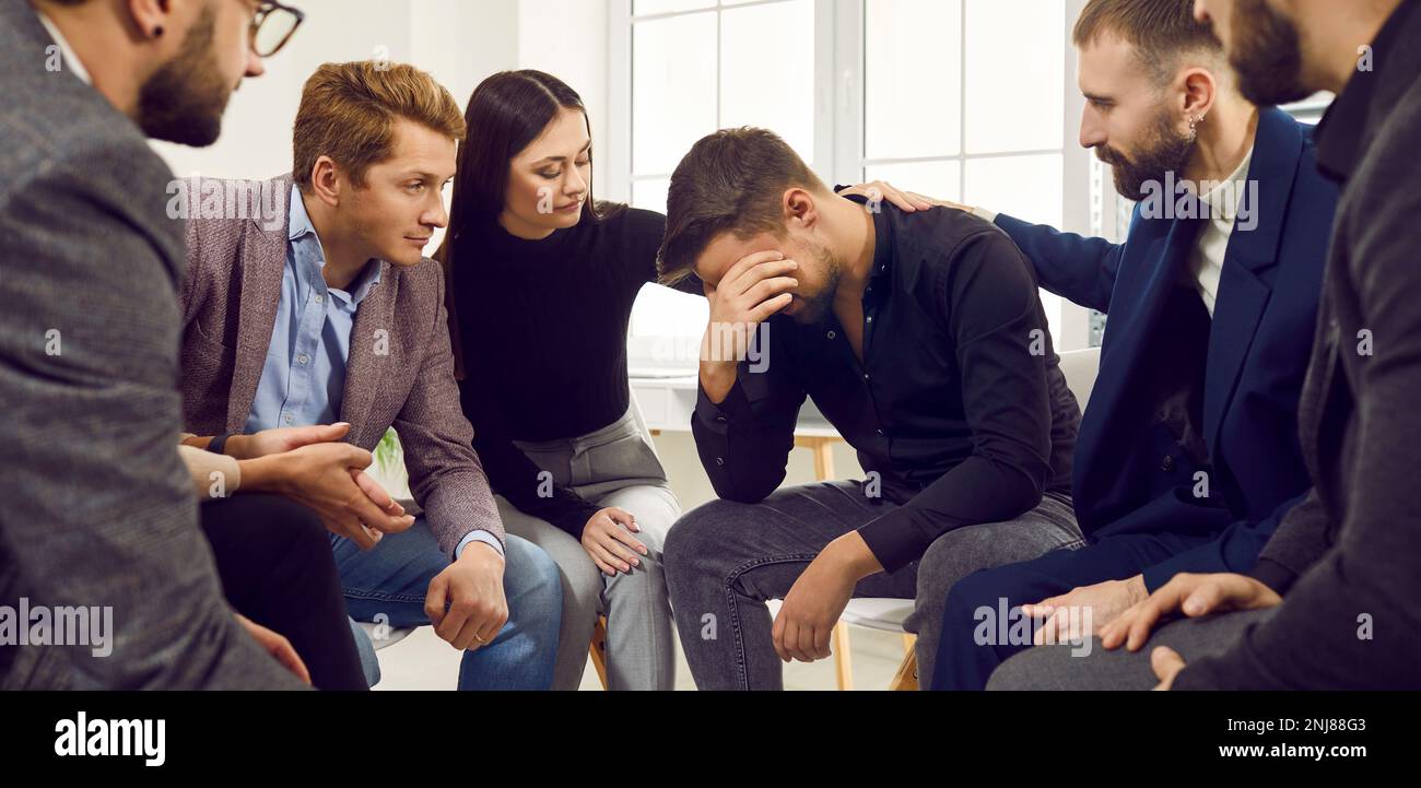Team of friends and colleagues comforting and supporting a sad man who ...