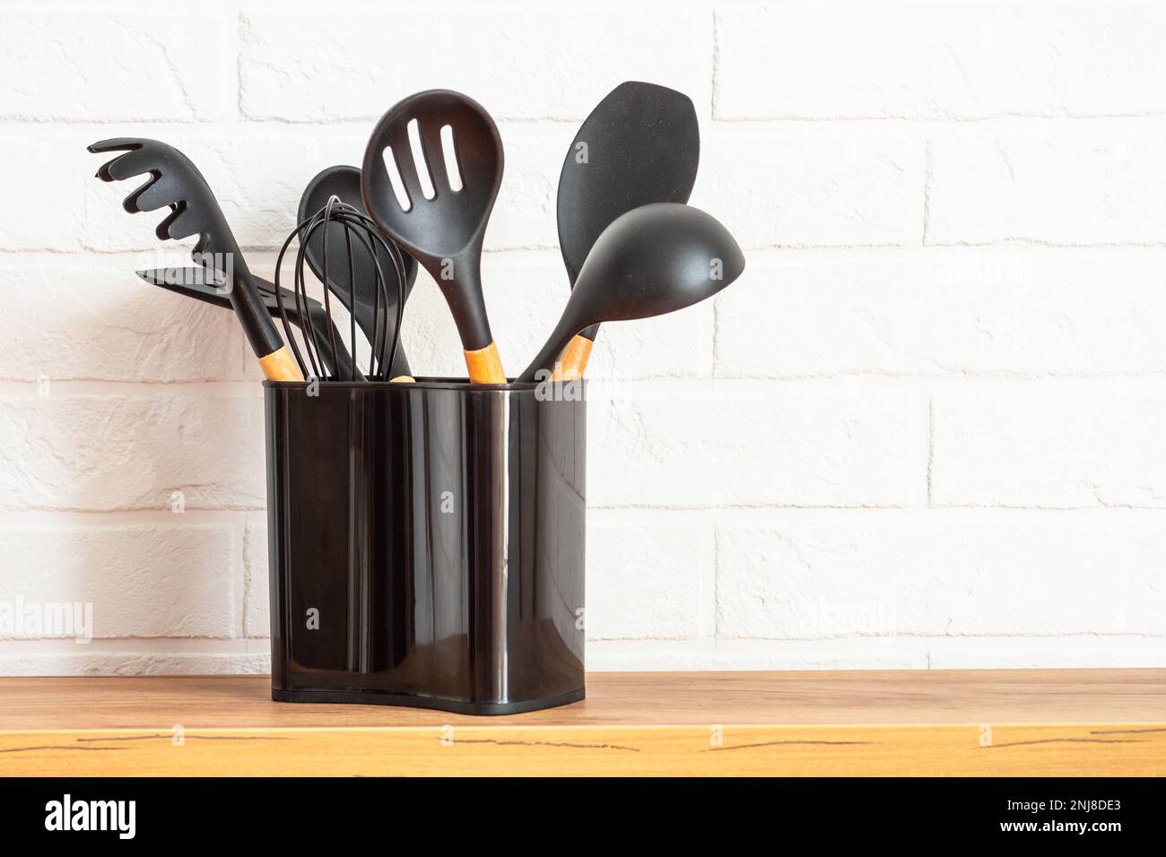 Kitchen utensils in container near white wall Stock Photo - Alamy