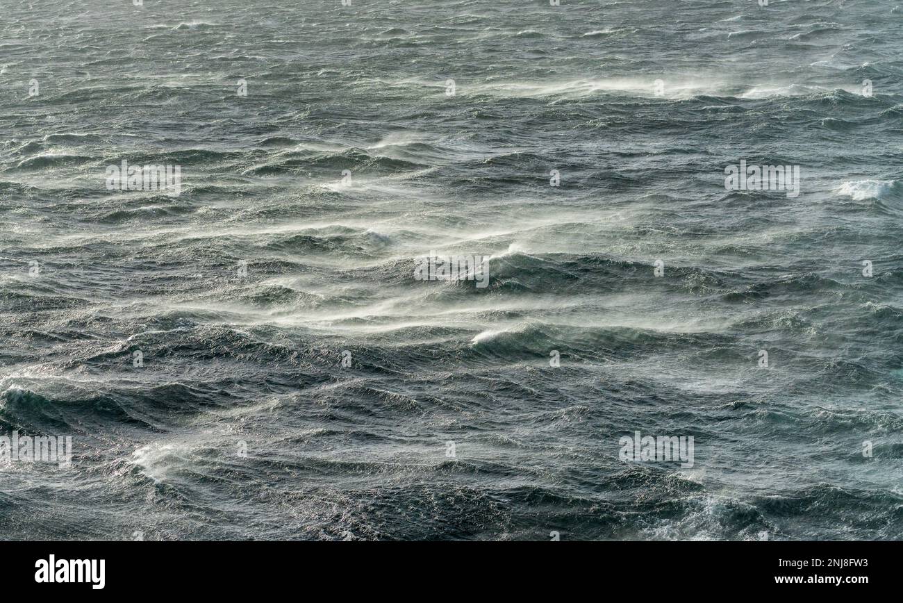 Strong windswept view of ocean near Cape Horn as wind blows white caps ...