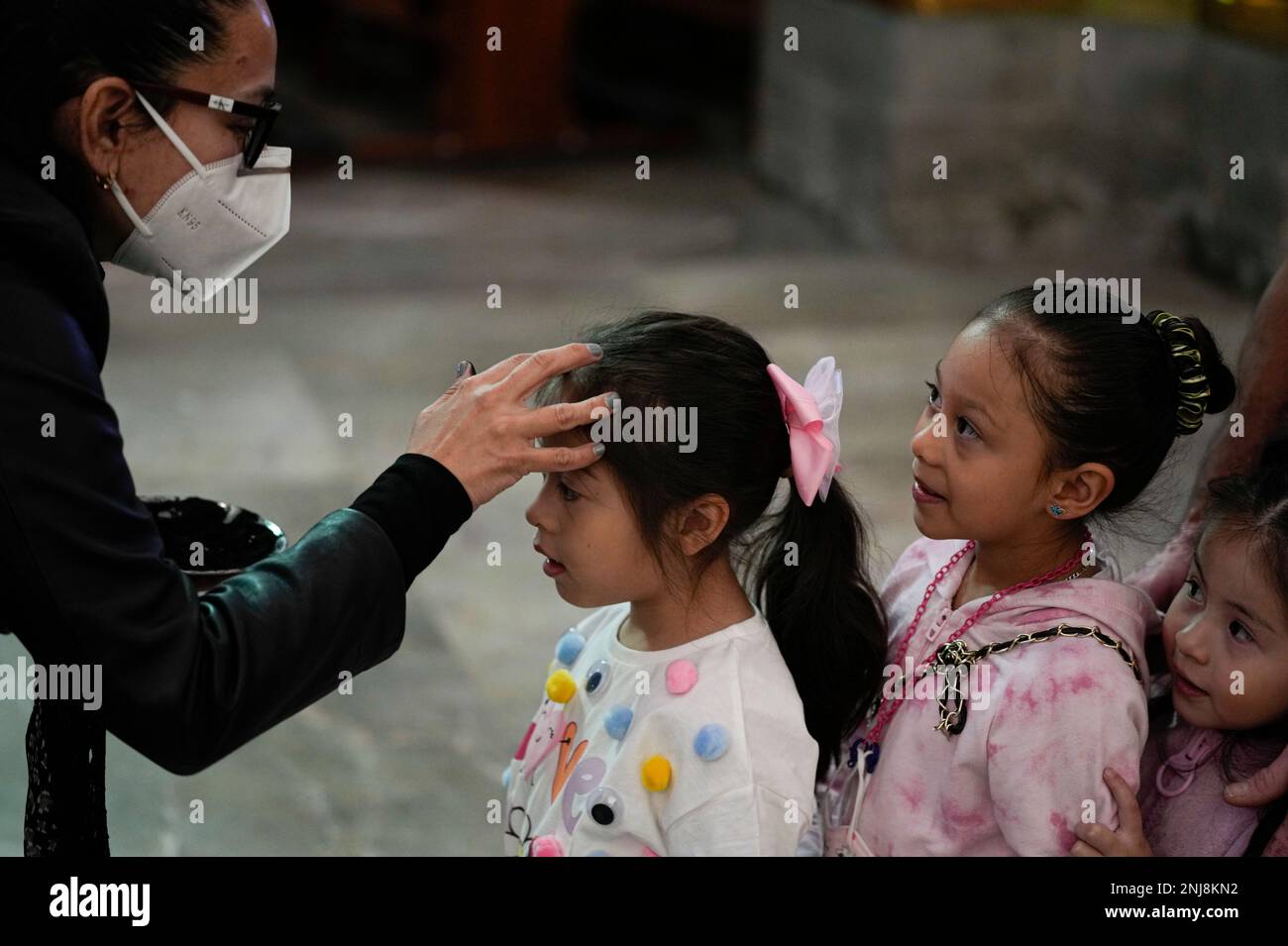 A deaconess marks the forehead of a child with an ash cross during an ...