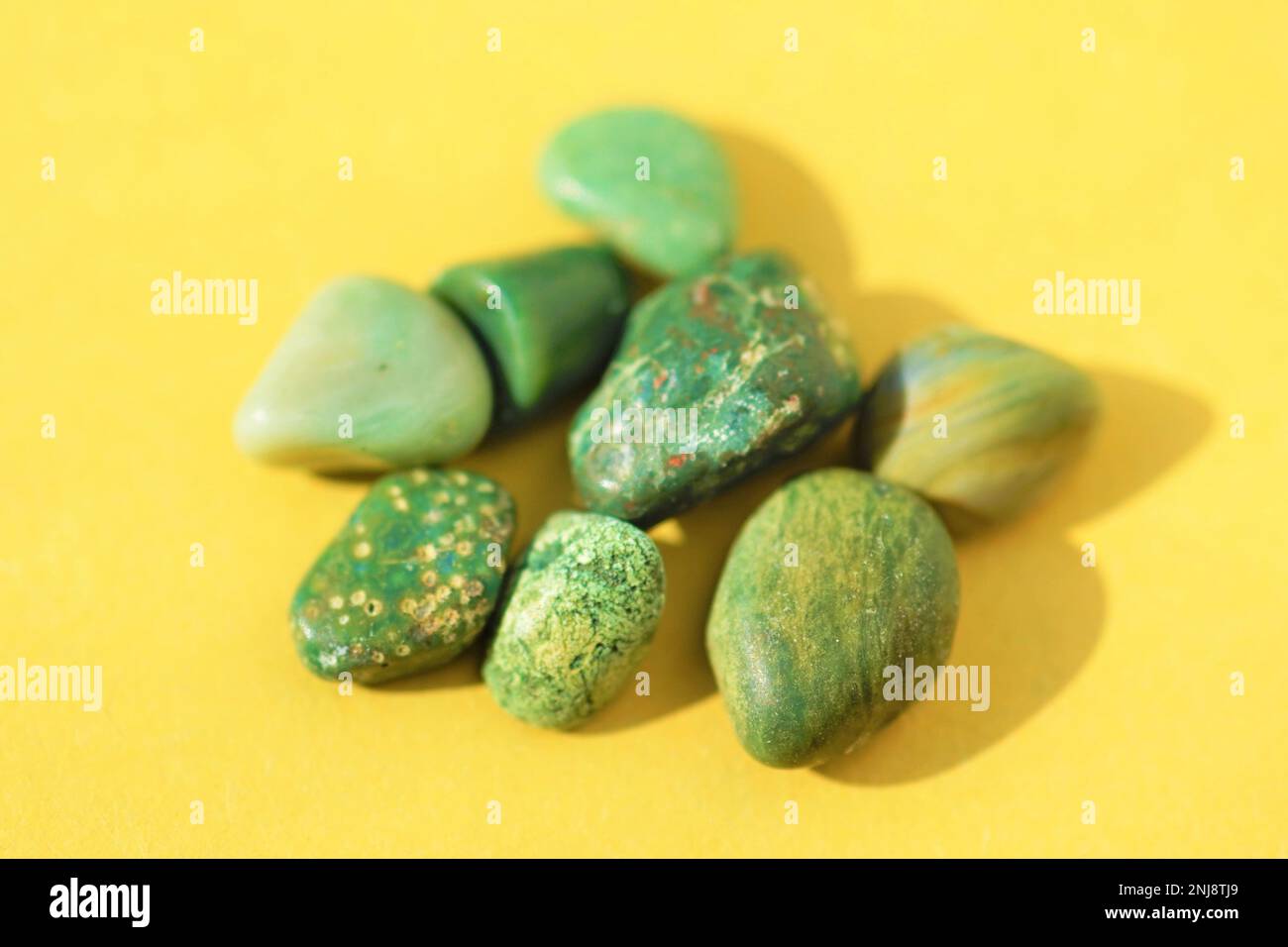 Heap of green pebble stones at yellow sunny table Stock Photo - Alamy