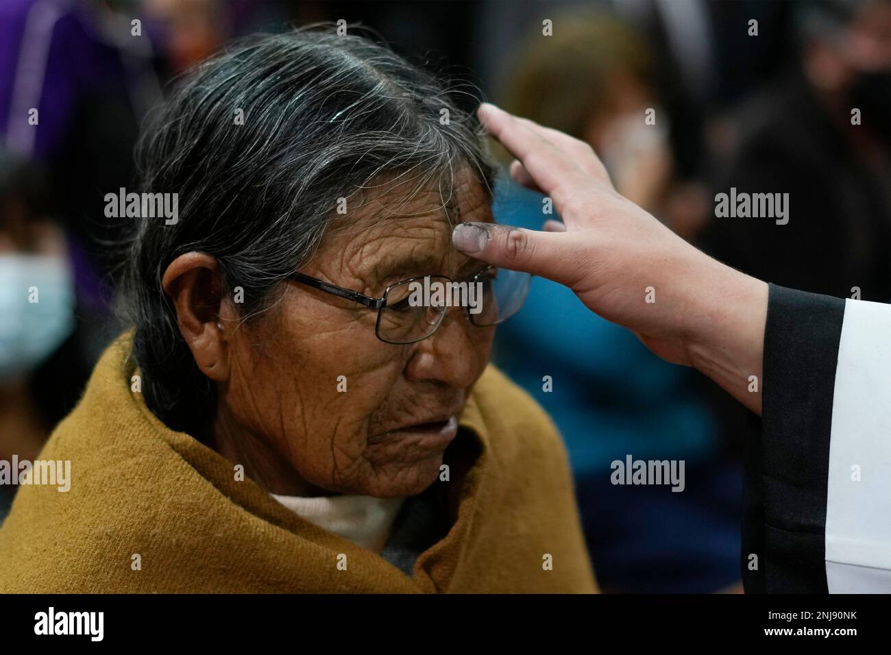 A Catholic priest marks the symbol of the cross on a person's forehead ...