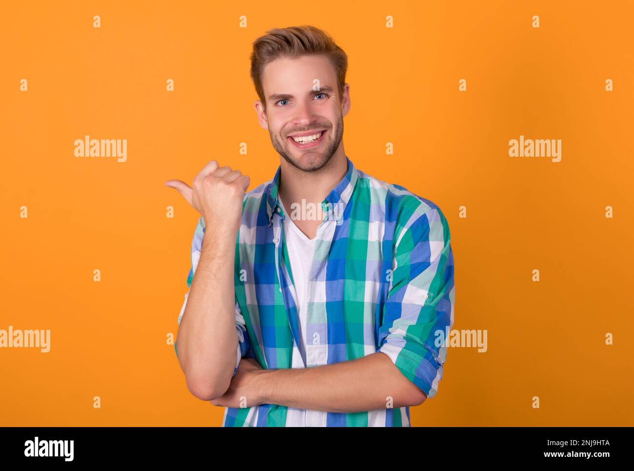 Your advert here. Happy man pointing thumb yellow background. Place ...