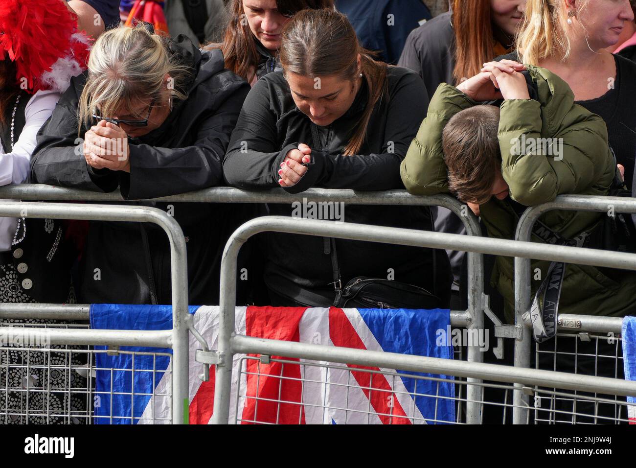 Members of the public bow their heads as they listen to the funeral ...