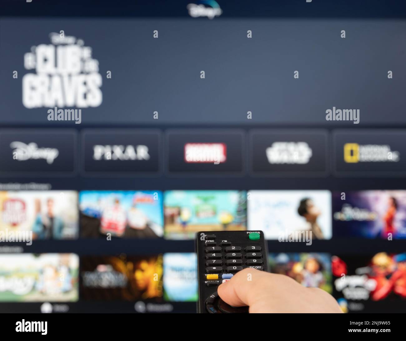 New york, USA - February 21, 2023: Select video on Disney stream service on tv with remote ...