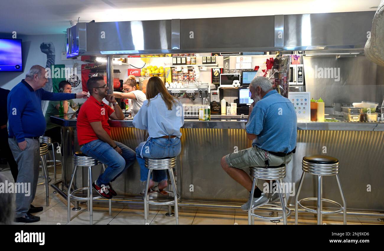 Bar with customers sitting on stools and woman behind counter Stock ...