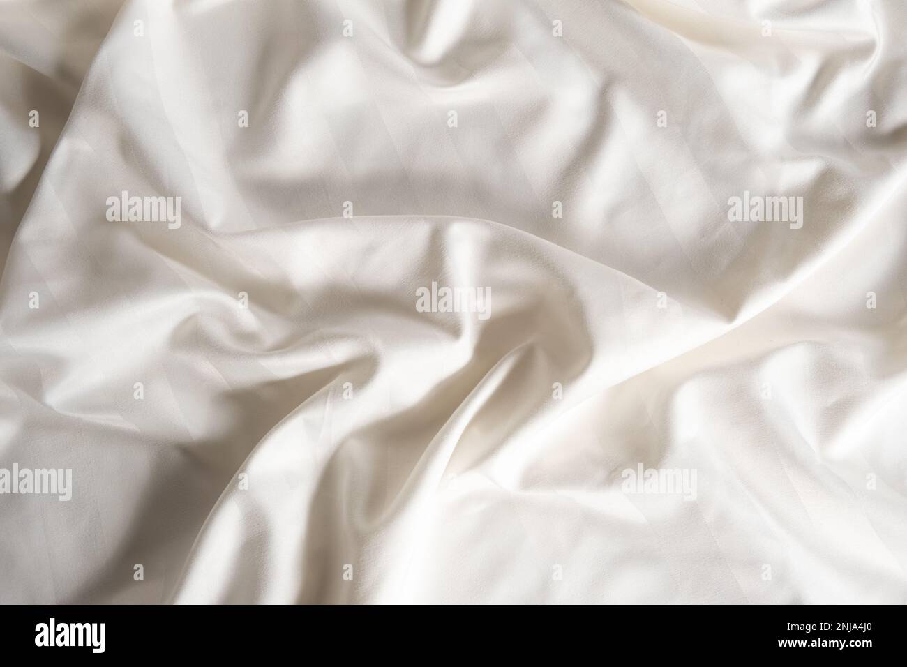 Satin crumpled fabric of light milky color, top view. Natural bed linen ...