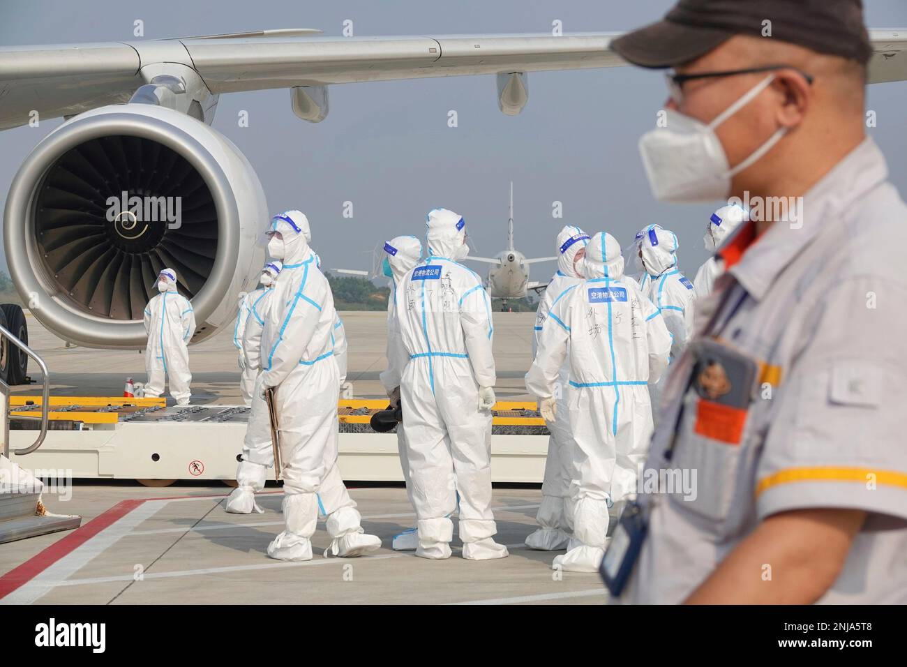 Chinese workers in PPE wait to serve an MNG Airlines cargo plane from ...