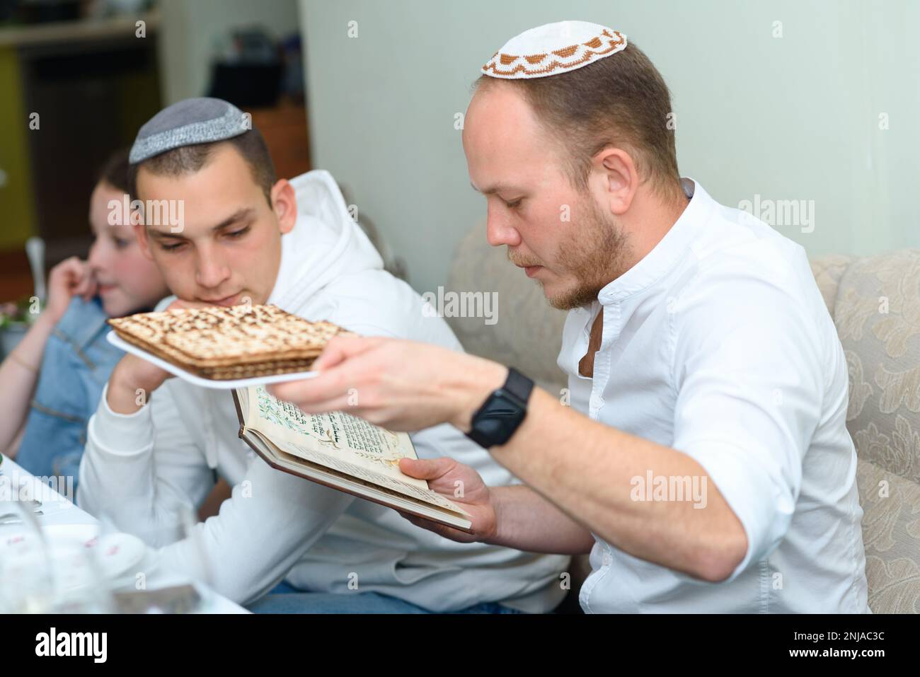 Jewish family celebrate Passover Seder reading the Haggadah. Young ...