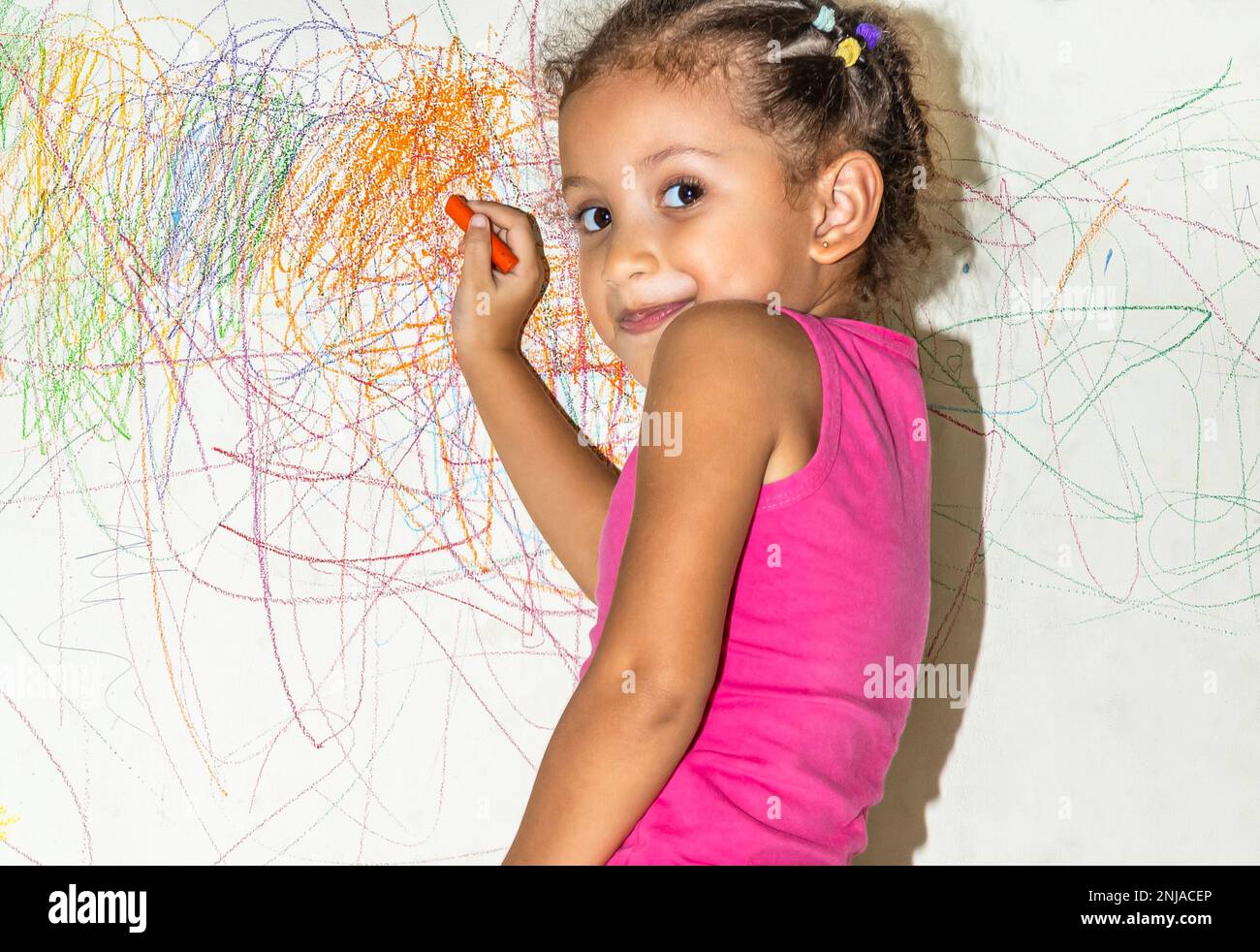 Little brazilian girl doodling, painting and drawing on light yellow ...