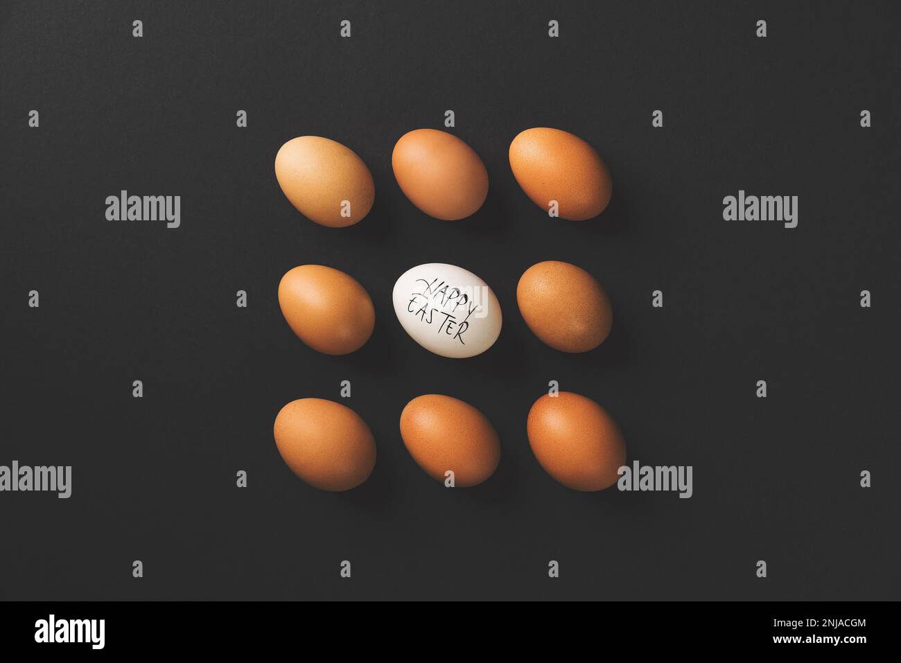 Brown chicken eggs flat lay on black background with one white Happy ...