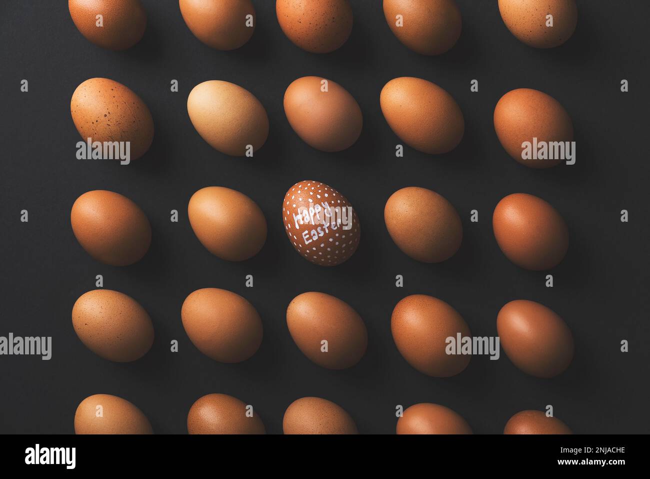 Brown chicken eggs flat lay on black background with one Happy Easter ...