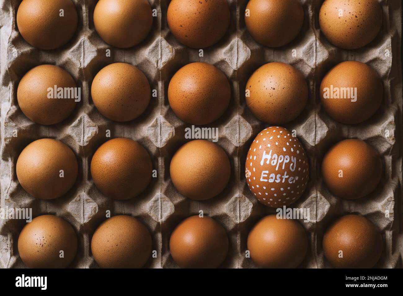 Box of eggs on black background with one happy easter written egg ...