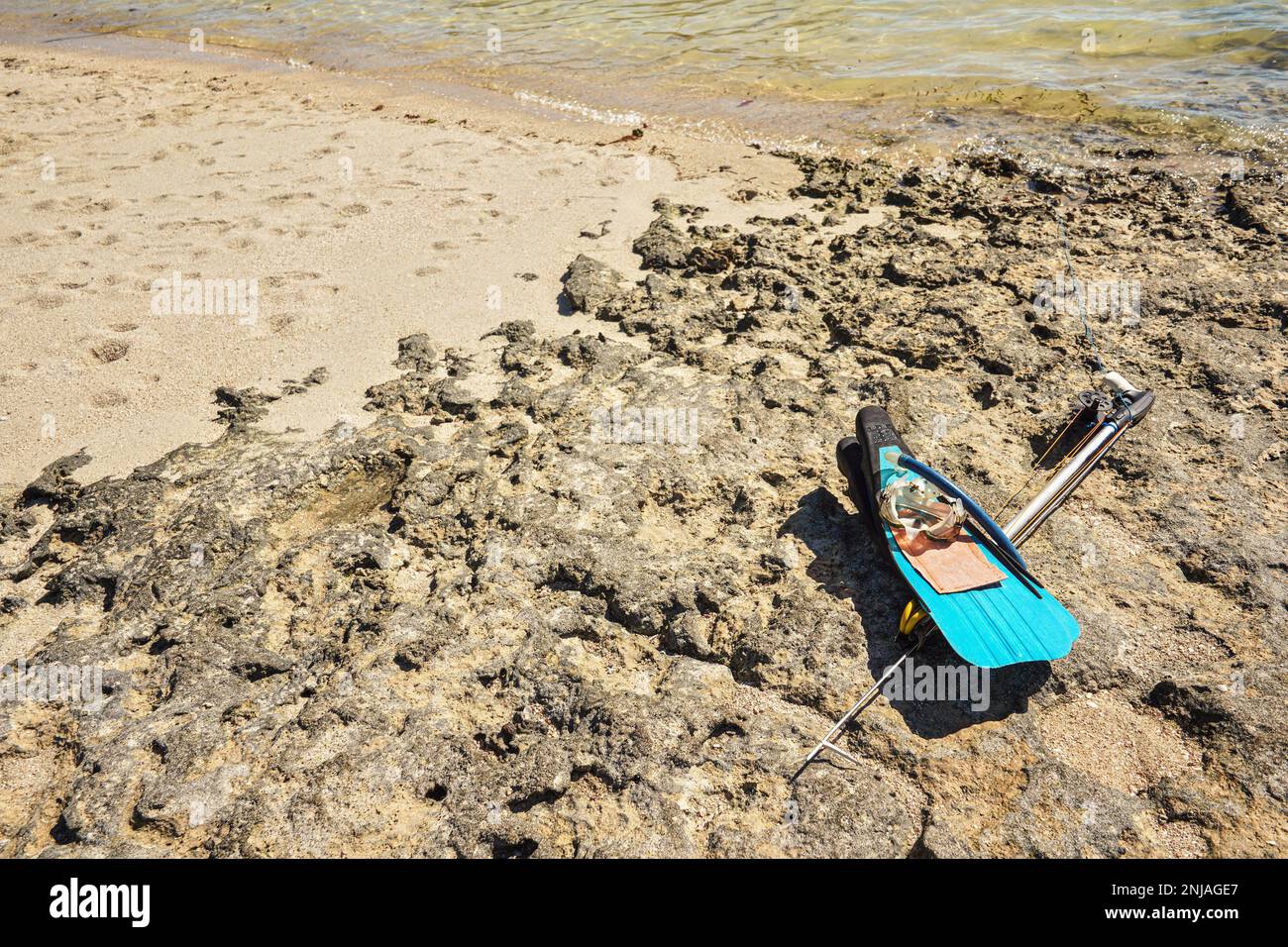 Snorkel, mask, fins and simple spear fishing harpoon on sun lit rocky ...