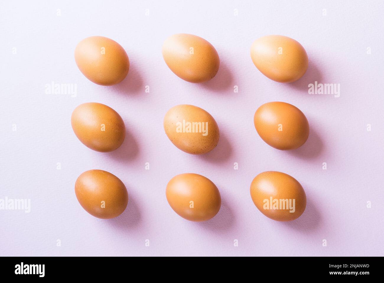 Nine brown eggs flat lay on purple background. Fresh organic free range ...