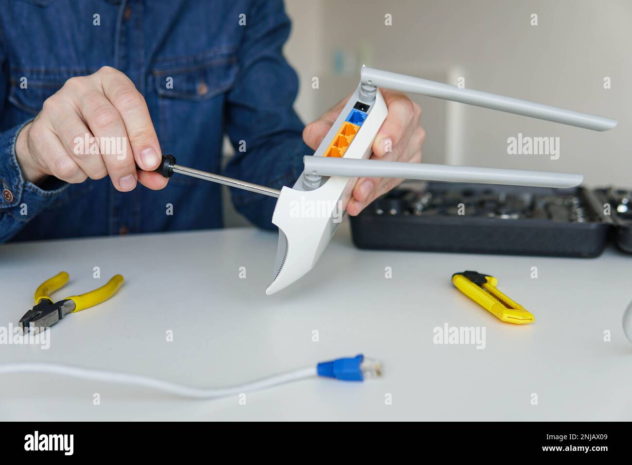 Young man repairing wifi router with screwdriver Stock Photo - Alamy