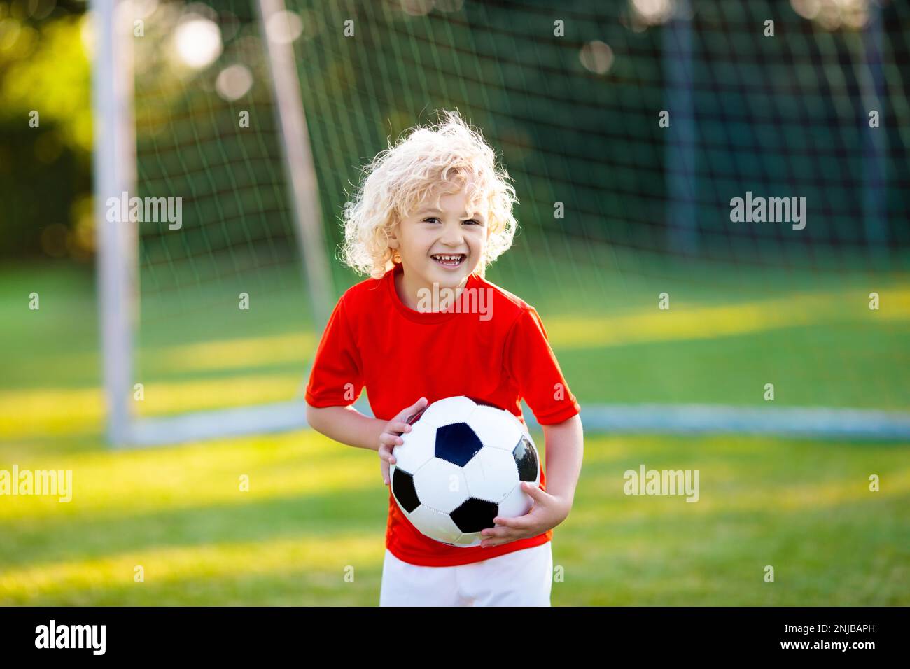 Kids play football on outdoor field. Children score a goal at soccer ...