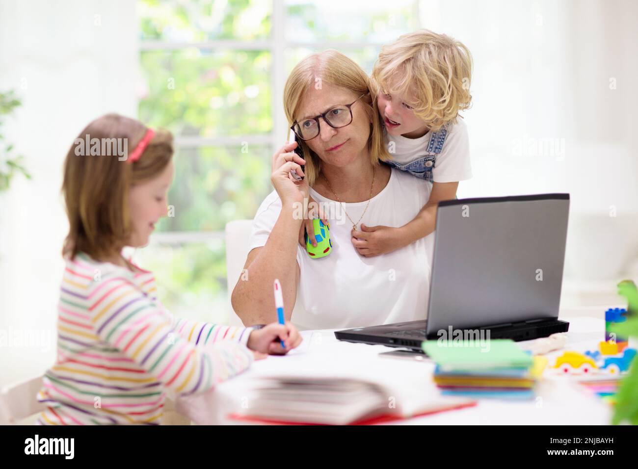 Mother working from home with kids on summer holiday. Children make ...