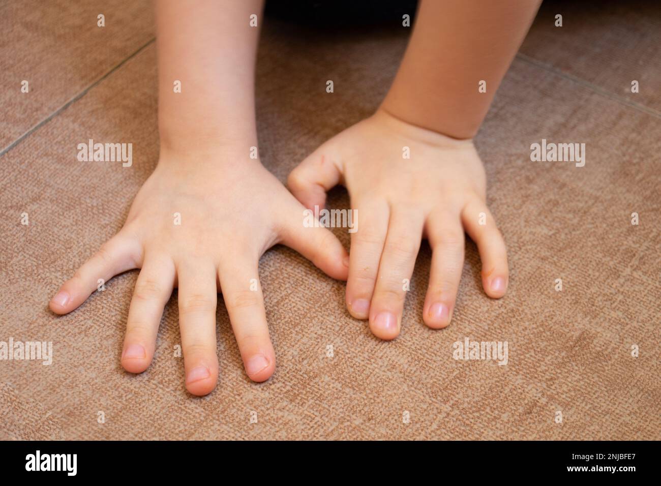 close-up of a small children's palm on a brown tile on the floor Stock ...