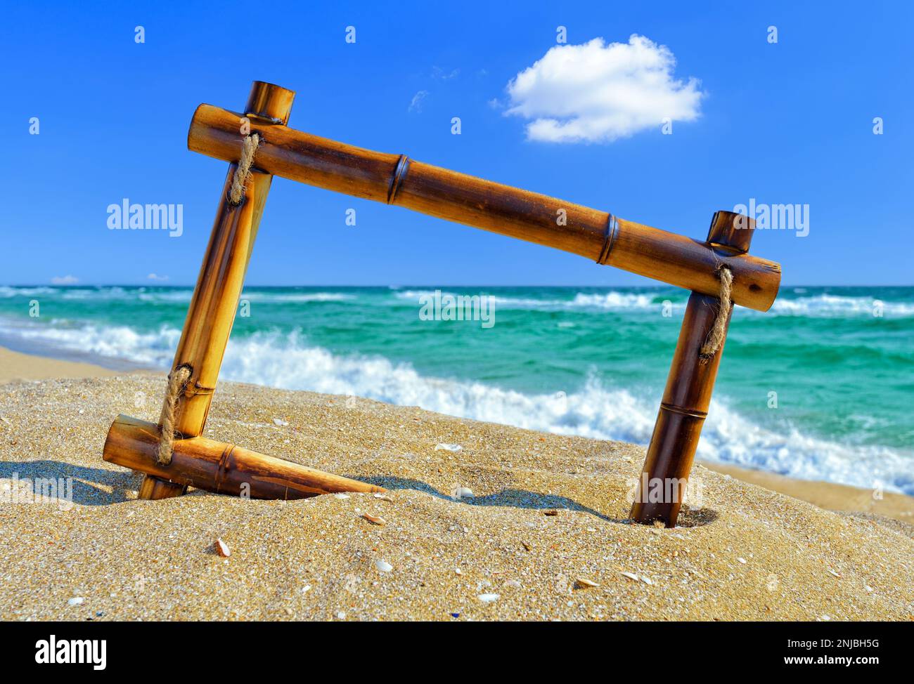 Summer seascape with a bamboo photo frame on the beach sand of a ...