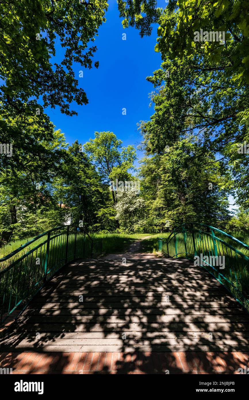 Old renovated retro bridge with green metal railings over small river ...