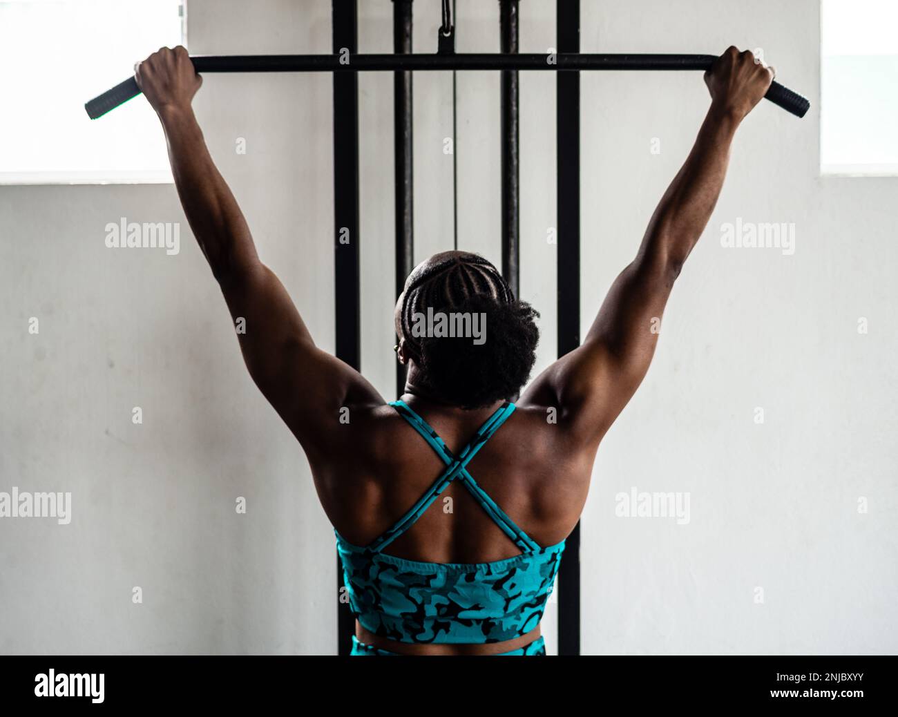 Portrait of muscular woman doing pull-up exercises for back muscles ...