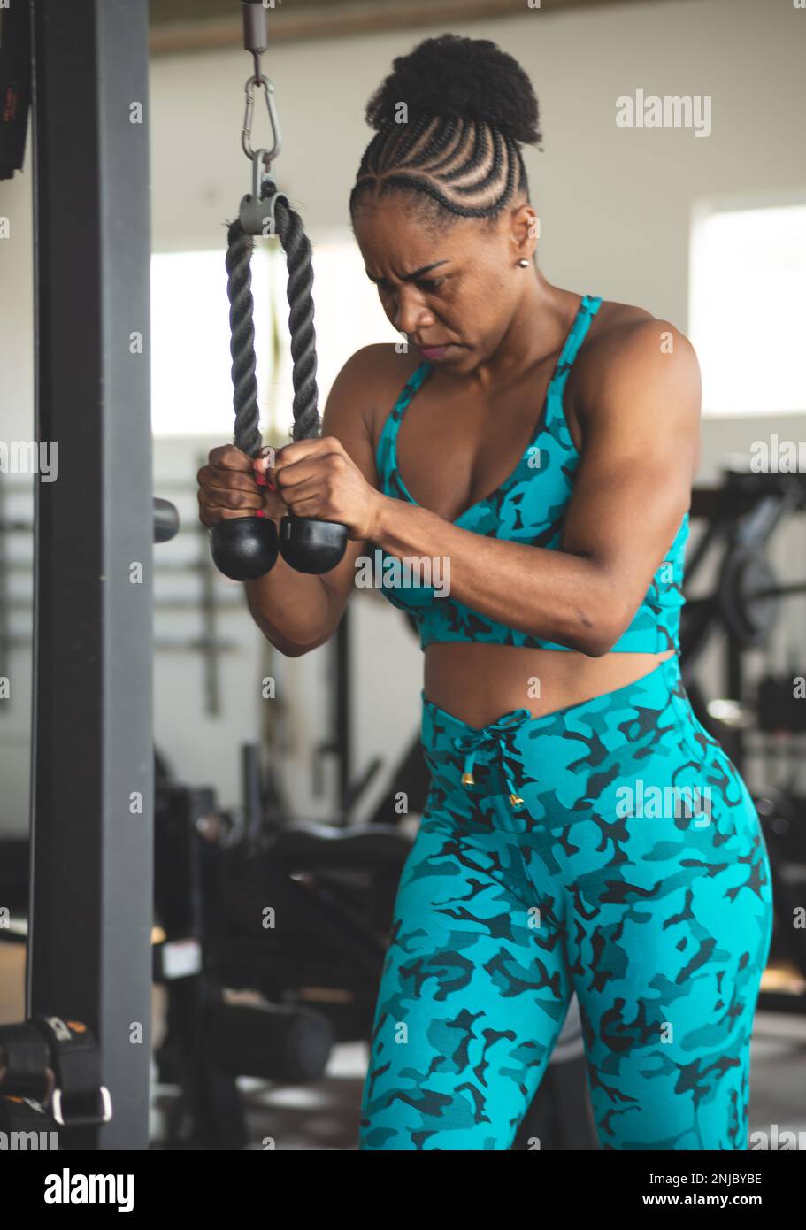 Sporty woman exercising pulley in studio. For arm and shoulder muscles ...