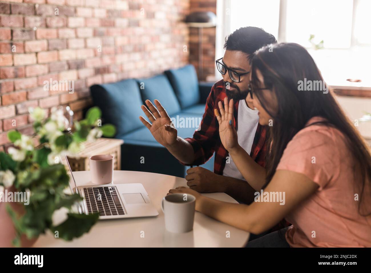 Happy indian family couple cuddle at desk make video call to friends ...