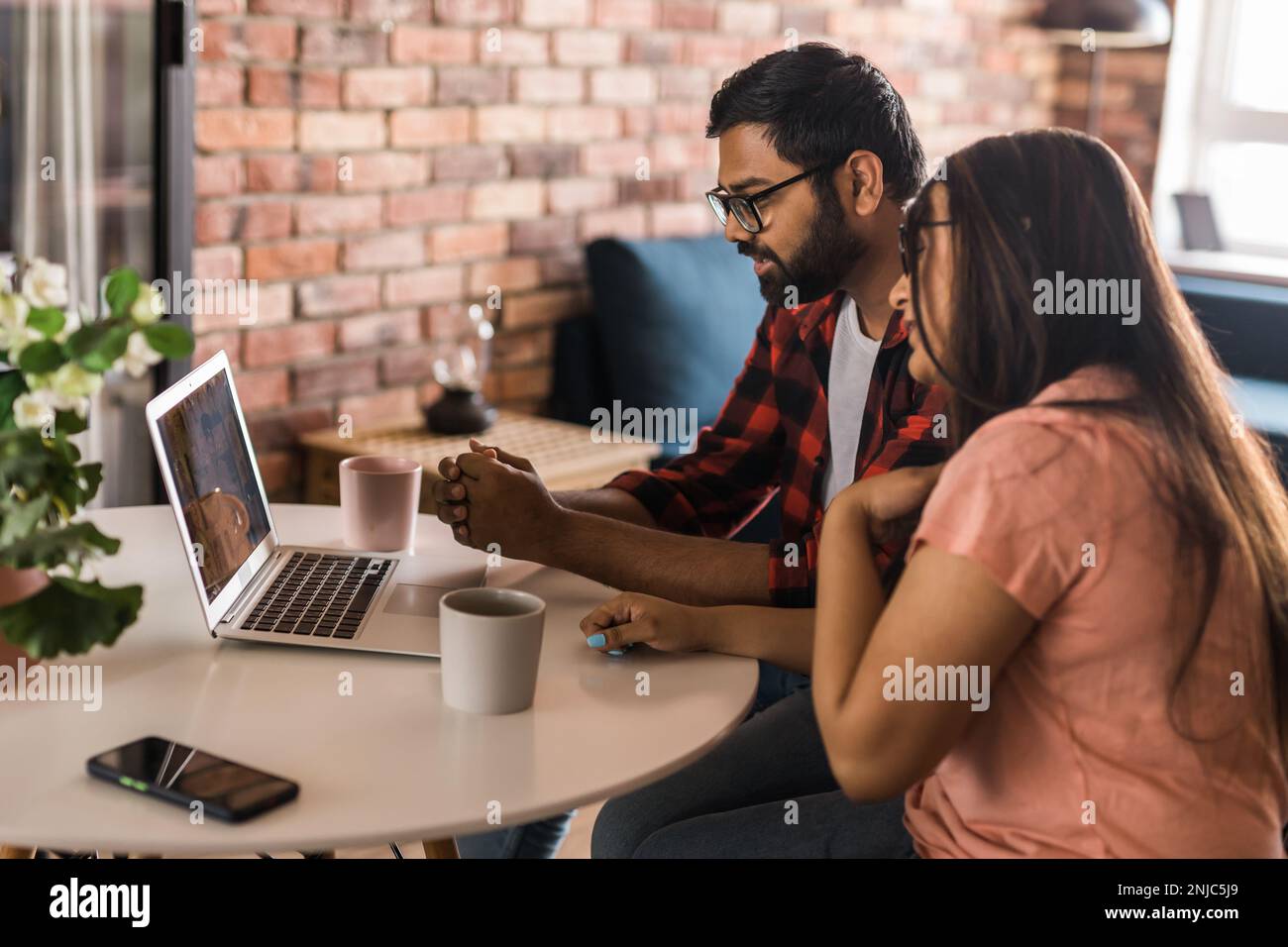 Happy indian family couple cuddle at desk make video call to friends ...