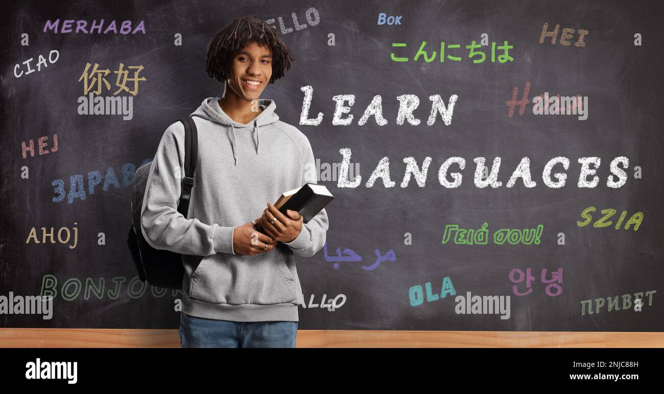 African american male student holding books in front of a blackboard ...