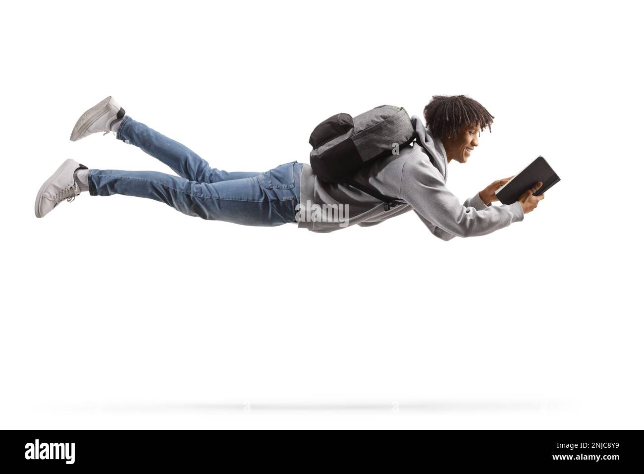 Full length shot of an african american male student flying and reading ...
