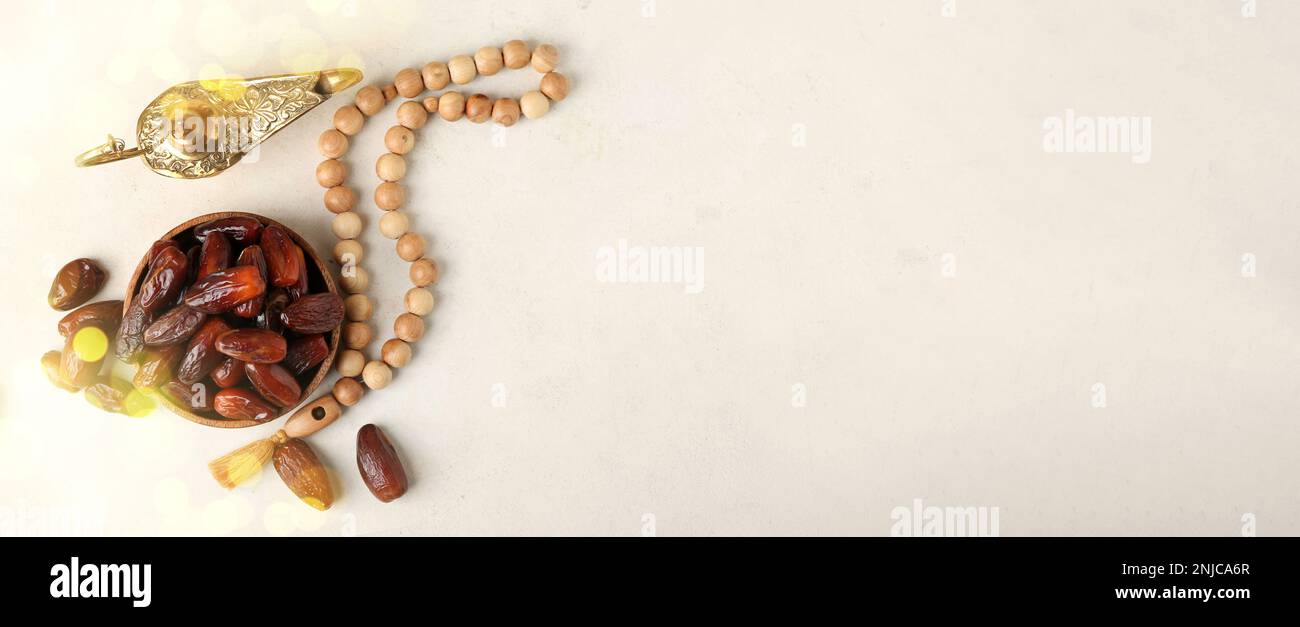 Tasty dates, prayer beads and Aladdin lamp on light background with ...