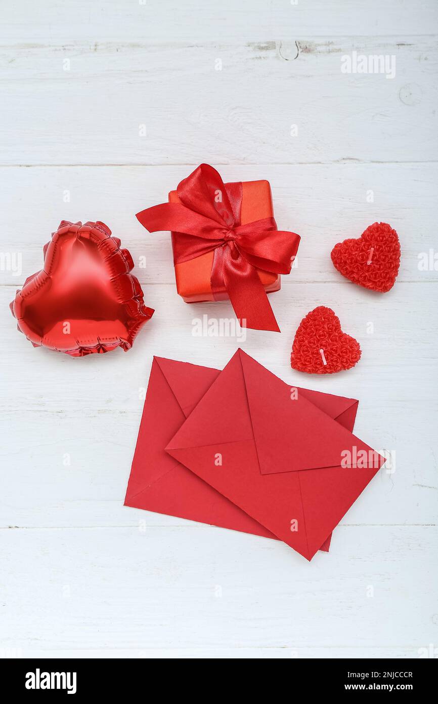 Composition with beautiful candles, envelopes, gift box and balloon on ...