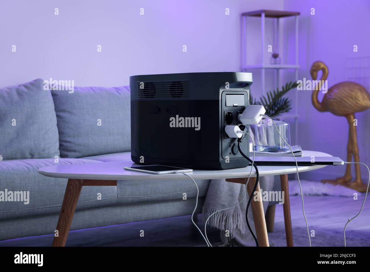Portable power station charging devices on table in living room Stock ...