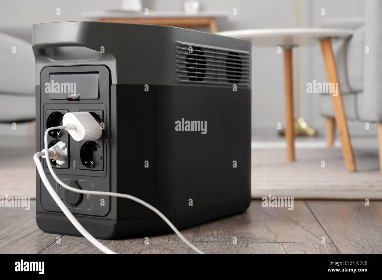 Portable power station charging devices on floor in living room Stock ...