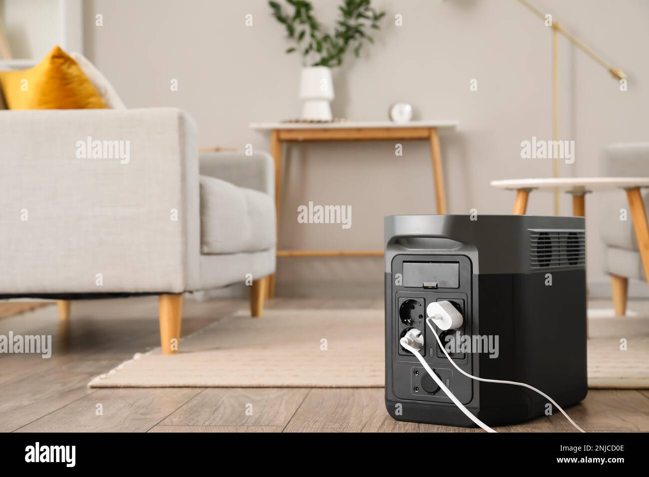 Portable power station charging devices on floor in living room Stock ...